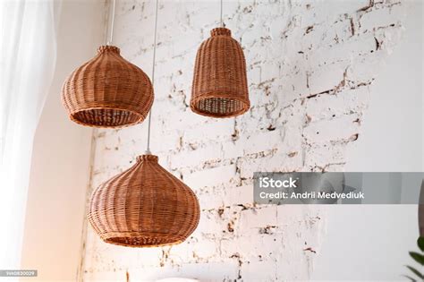 세 개의 등나무 샹들리에는 흰색 벽돌 벽 배경에 다른 형태입니다 아늑한 거실에 있는 짚 전등갓 천연 소재를 사용한 친환경 인테리어 디자인 스칸디나비아 인테리어 복사 공간