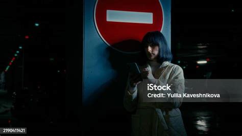 전체 높이 촬영 여성 여성 여성 사업가 운전사 주차장 정류장 진입 금지 도로 표지판 붉은 벽돌 휴대 전화 채팅 예약 자동차 택시 스마트 폰 앱을 사용하는 자동차 택시