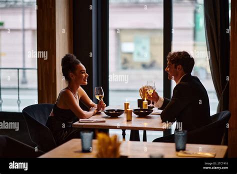 Happy Interracial Couple In Elegant Attire Holding Glasses With Wine