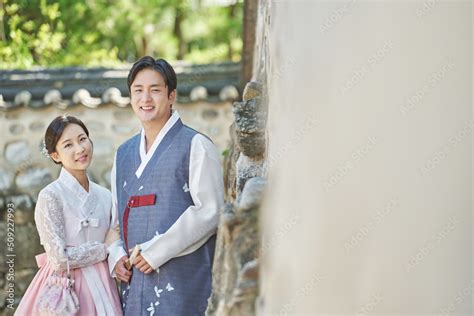 한복을 입고 한국의 전통 가옥 담장을 배경으로 커플 여행자 아름답고 멋진 젊은 아시아 한국 남녀 모델 스톡 사진 Adobe Stock