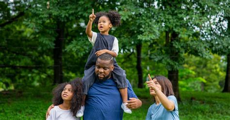 공원에서 행복한 혼혈 가족 아프리카인 아버지와 아시아인 어머니 두 어린 딸이 손을 잡고 정원에서 함께 걷고 있다 아이 소녀 아이와 함께 엄마와 아빠는 야외 라이프