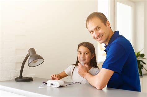 집에서 분무기로 흡입하는 어린 유아 소녀 아버지가 장치를 돕고 들고 계십니다 독감 기침 및 기관지염을 가진 아이 천식 흡입기