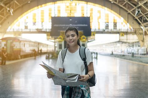 기차역에 도착한 젊은 여성이 지도 확인 경로를 보고 있습니다 흰색 티셔츠와 청바지를 입고 배낭을 뒤로 하고 기차역에서 지도를