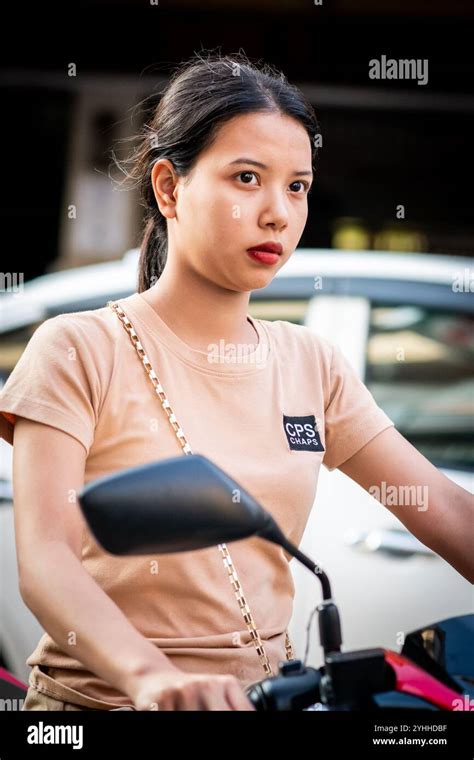 A Beautiful Young Thai Girl Sat On A Motorbike Or Scooter Makes Her Way