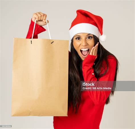 젊은 여자 종이 쇼핑백 빨간색과 산타 클로스 모자와 함께 크리스마스에 대 한 준비가 회색 배경 크리스마스 쇼핑 선물 축 하 소비와 판매 개념에 대 한 준비가 되 고 고립