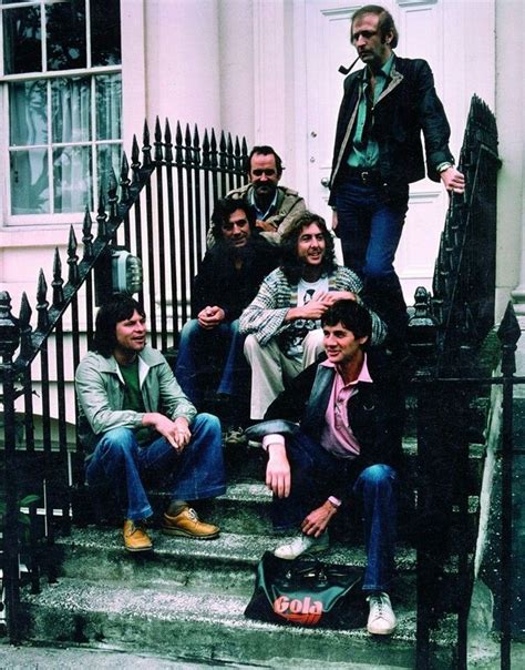 A Group Of People Sitting On The Steps Of A Building In Front Of A Gate