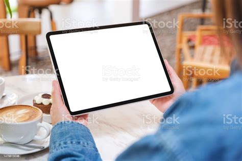 카페의 테이블에 케이크와 커피 컵이 있는 빈 흰색 데스크톱 화면이 있는 디지털 태블릿을 들고 있는 여성의 모형 이미지 35 39