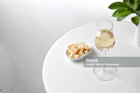 풍부한 유리를 곁들인 화이트 와인이 녹색 치즈 화병이 있는 흰색 원형 테이블에 올려놓습니다 미니멀리즘 우아한 사진 이미지에 대한 스톡 사진 및 기타 이미지 Istock