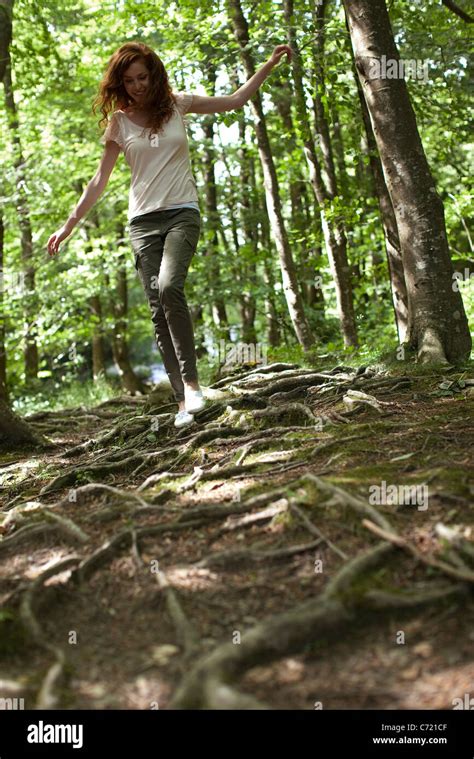 Woman Walking On Tree Roots In Woods Stock Photo Alamy