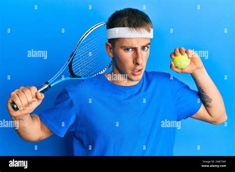 Young Caucasian Man Playing Tennis Holding Racket And Ball Clueless And