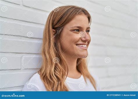 Jovencita Rubia Sonriendo Confiada Mirando Al Costado Sobre Fondo