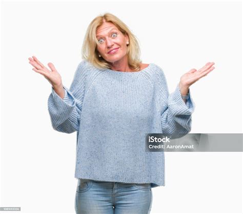 중간 나이 금발 여자 팔과 손을 제기와 격리 된 배경 우 둔 하 고 혼란 스 러 워 식 이상의 겨울 스웨터를 입고 의심 개념입니다 감정에 대한 스톡 사진 및 기타 이미지