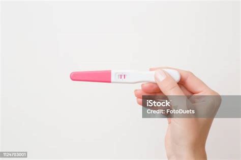 회색 바탕에 줄무늬 두 임신 테스트를 개최 하는 젊은 여자의 손 긍정적인 결과입니다 근접 촬영입니다 포인트 보기 샷입니다