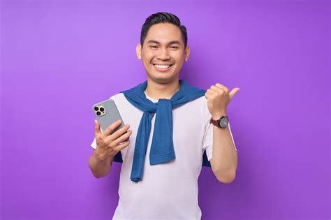 Premium Photo Cheerful Young Asian Man Using Mobile Phone And Showing