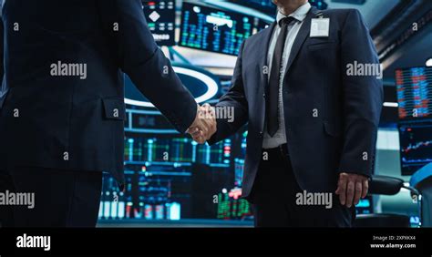 Two Anonymous Stock Market Traders Shaking Hands In A Technologically Advanced Office With