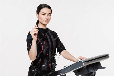 전기 자극을 사용하여 흰색 배경에 근육을 자극하는 접촉기를 손에 들고 Ems 슈트에 맞는 소녀 전기 근육 자극 슈트의 스포츠 훈련 프리미엄 사진