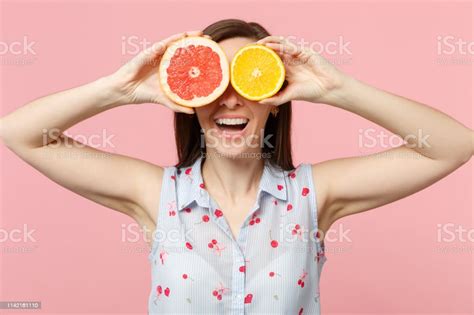 분홍색 파스텔 배경에 고립 된 신선한 잘 익은 자 몽 오렌지 과일의 Halfs와 눈을 덮고 여름 옷에 재미 있는 어린 소녀 사람들은 생생한 라이프 스타일 휴식 휴가