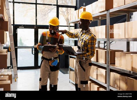 warehouse coworkers using laptop inventory software and writing in