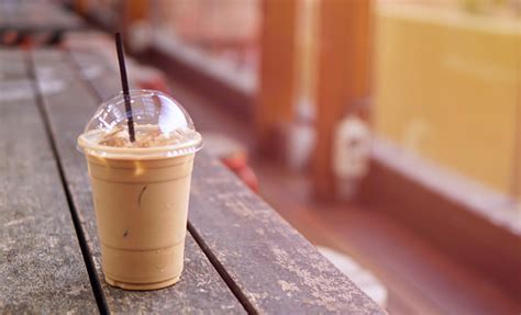 나무 테이블에 테이크 아웃 컵 라 떼 커피 얼음 나무 테이블에 짚으로 플라스틱 컵에 테이크 아웃 아이스 라 떼 나무 테이블에