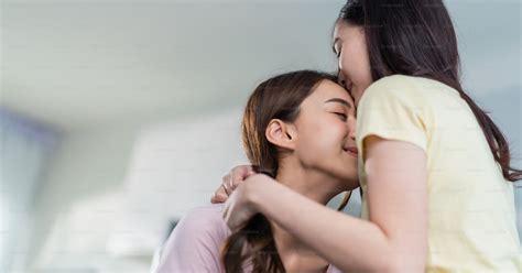 아시아의 아름다운 레즈비언 여성 커플이 집에서 여자 친구 머리를 빗질하고 있다 매력적인 두 여자 게이 친구가 거실의 소파에 앉아 함께 미용 화장품에 행복을 느낀다 동성애