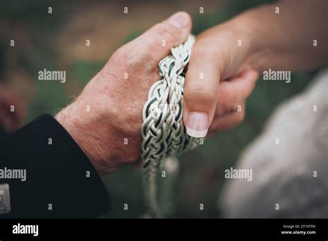 Close Up Picture Of Bride And Groom S Hands Tied With White And Green