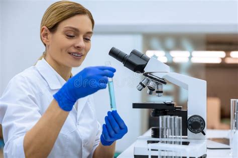 Attractive Female Scientist Examining Liquid In Test Tube In Laboratory Doing DNA Researching