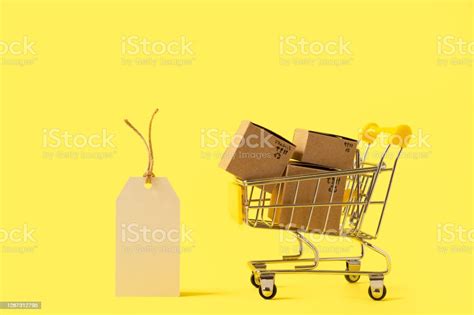 노란색 배경에 상자와 빈 태그장난감 쇼핑 카트 텍스트 또는 디자인공간을 복사합니다 판매 할인 쇼핑 및 배달 개념 소비자 사회