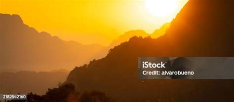 하늘과 풍경은 강렬한 오렌지색으로 물들고 모든 종류의 입자가 공기 중에 떠 다니며 거의 꿈처럼 방비엥 라오스 동남아시아 근처에 있습니다 0명에 대한 스톡 사진 및 기타