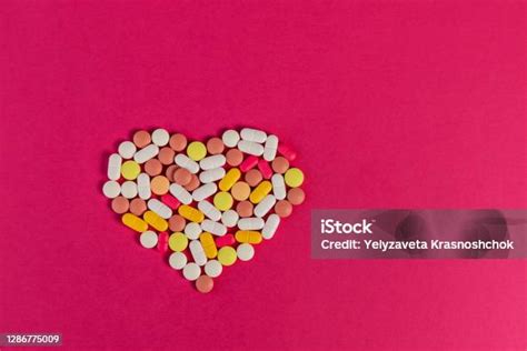 많은 다른 알 약과 정제 핑크 배경에 심장의 모양으로 접혀 텍스트에 대 한 공간이 많은 알 약과 정제 의료 맨 위 보기입니다