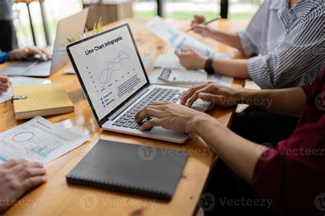 Business Team Discuss Data Analysis With Line Charts Infographic On Laptop In Modern Office