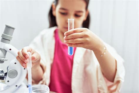 실험실에서 실험을 수행하기 위해 액체가 함유 된 플라스크를 보는 과학자 어린 소녀 학교에서 현미경과 함께 화학 실험실 실험을 테스트하는 아이 Stem 주제에 대한 스톡 사진