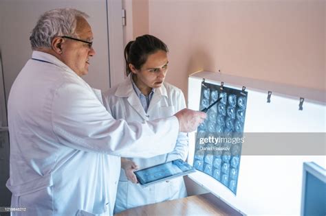 Two Surgeons Discussing Ct Scan Of A Head And A Mri Scan Of A Shoulder