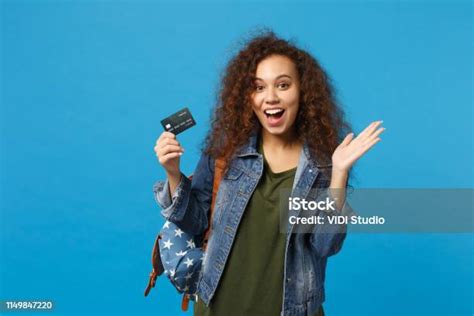 데님 옷 배낭 홀드 신용 카드 파란색 배경 스튜디오 초상화에 고립에서 젊은 아프리카계 미국인 소녀 십 대 학생 고등학교 대학 대학 컨셉의 교육 복사 공간을 모의 가방에 대한