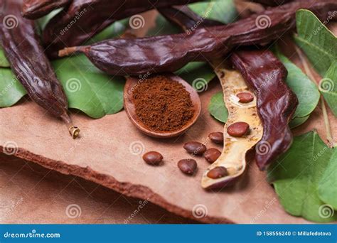 Carob Organic Carob Pods With Seeds And Leaves On Tree Bark Table