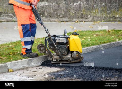 Paving Worker Uses Vibratory Plate Compactor To Compact New Asphalt