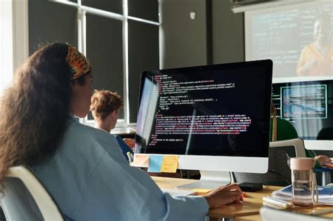 Premium Photo Rear View Of Babegirl Sitting At Desk In Front Of Computer Monitor And Working