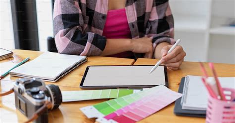 Cropped Shot Of Young Female Designer Student Doing Assignment On Digital Tablet And Designer Cropped Shot Of Young Female Designer Student Doing Assignment On Digital Tablet And Designer
