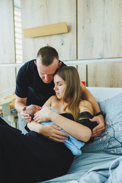 Uma Jovem Mãe E Pai Abraçam Seu Filho Recém Nascido Uma Mulher Amamenta