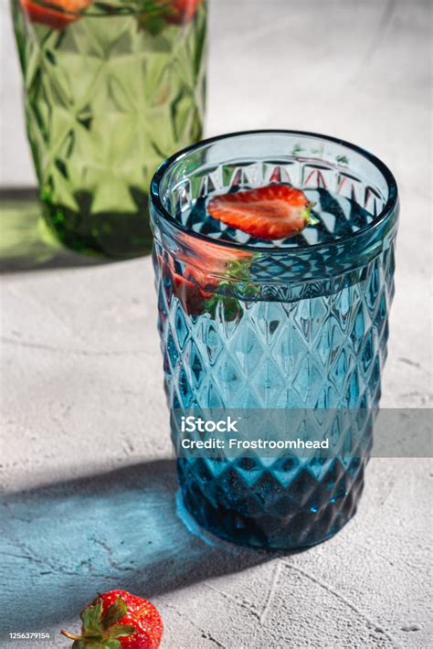 석조 콘크리트 배경에 화려한 그림자 광선과 신선한 물과 딸기 과일을 두 녹색과 파란색 기하학적 유리 컵 각도 보기 0명에 대한 스톡 사진 및 기타 이미지 Istock