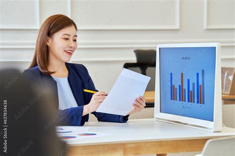 Fotografia Do Stock 비즈니스우먼 회사 업무 근무 사무실 모니터 앞에 앉아 서류 보며 업무을 보고 있는 직장인 모습 Adobe Stock