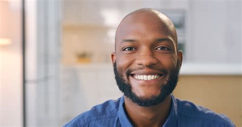 집이나 집에서 휴식을 취하는 동안 흥분하고 즐겁고 자신감을 느끼는 흑인의 행복하고 미소와 얼굴 차분한 젊은 수염과 아프리카 계 미국인 남성의 차가워진 머리와 초상화 휴식