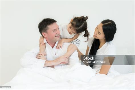 아름 다운 어머니와 함께 가족 귀여운 작은 딸과 함께 잘생긴 아버지는 얘기와 함께 침대에에서 시간을 보내는 동안 웃 고 행복 한 가족 개념입니다 가족에 대한 스톡 사진 및