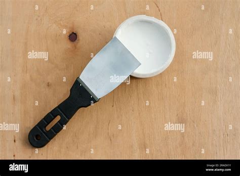 Construction Putty Knife And Can Of White Putty On Plywood Surface