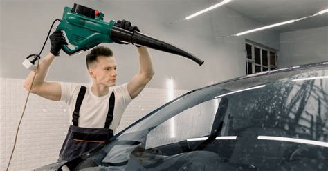 세차 및 디테일링 개념 전문 젊은 남성 자동차 서비스 노동자 특수 기계를 들고 물로 씻은 후 젖은 차를 말리십시오 사진