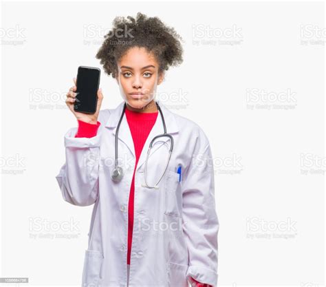 젊은 아프리카 미국 의사 여자 스마트 얼굴 심각한 생각에 자신감이 식으로 고립 된 배경 위에 스마트폰을 사용 하 여 감정에 대한