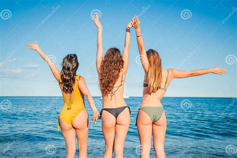 Rear View Of Three Beauty Young Women Spreading Their Arms On The Sand