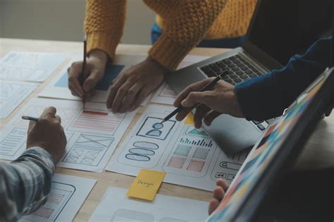 Ux 개발자 및 Ui 디자이너가 최신 사무실에서 고객 브리프 및 색상 코드를 사용하여 테이블의 모바일 앱 인터페이스 와이어프레임 디자인에 대해 브레인스토밍하는 닫기