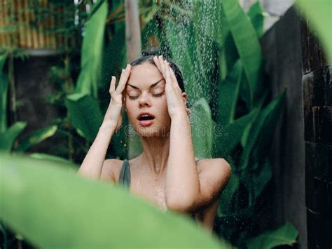A Woman Takes A Shower And Washes Her Head And Hair Outdoors Against The Backdrop Of Tropical