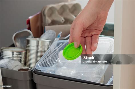 여자는 쓰레기를 분류하기 위한 4개의 용기 중 하나에 플라스틱 뚜껑 캔을 던진다 그녀의 재활용 부엌 서랍에 쓰레기를 넣는 여자 손 40 44세에 대한 스톡 사진 및 기타