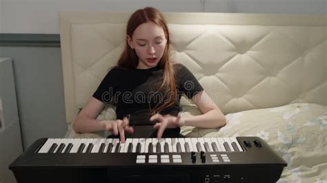 Young Woman Composing Music With Midi Keyboard On Bed Stock Video